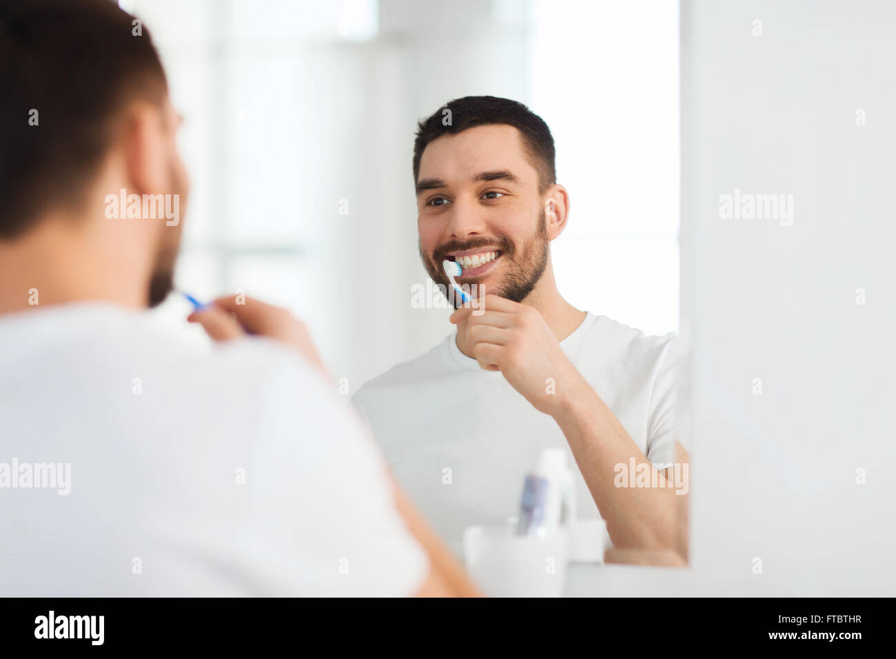 man with toothbrush cleaning teeth at bathroom Stock Photo - Alamy