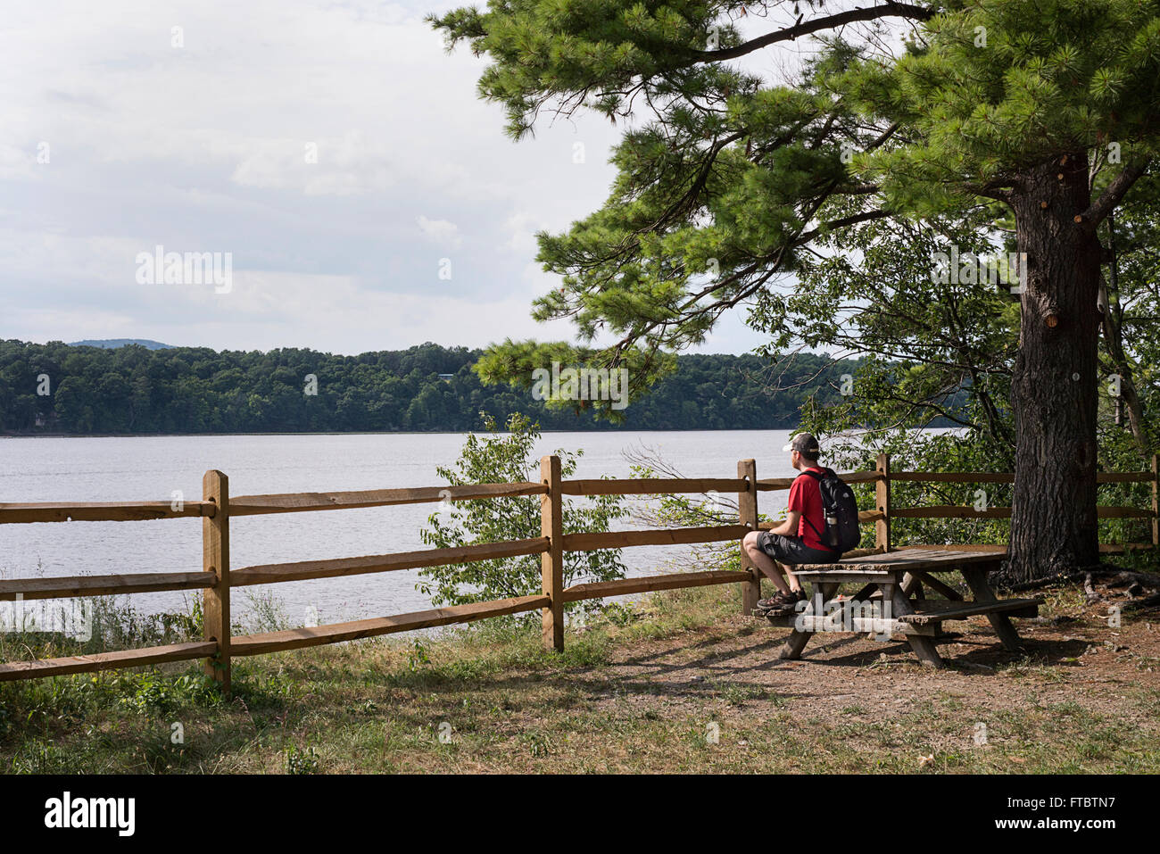 A man getting away from it all, sitting along the Hudson river in ...