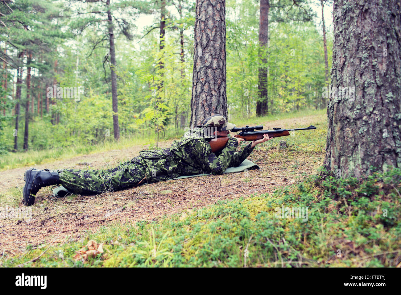 young soldier or hunter with gun in forest Stock Photo - Alamy