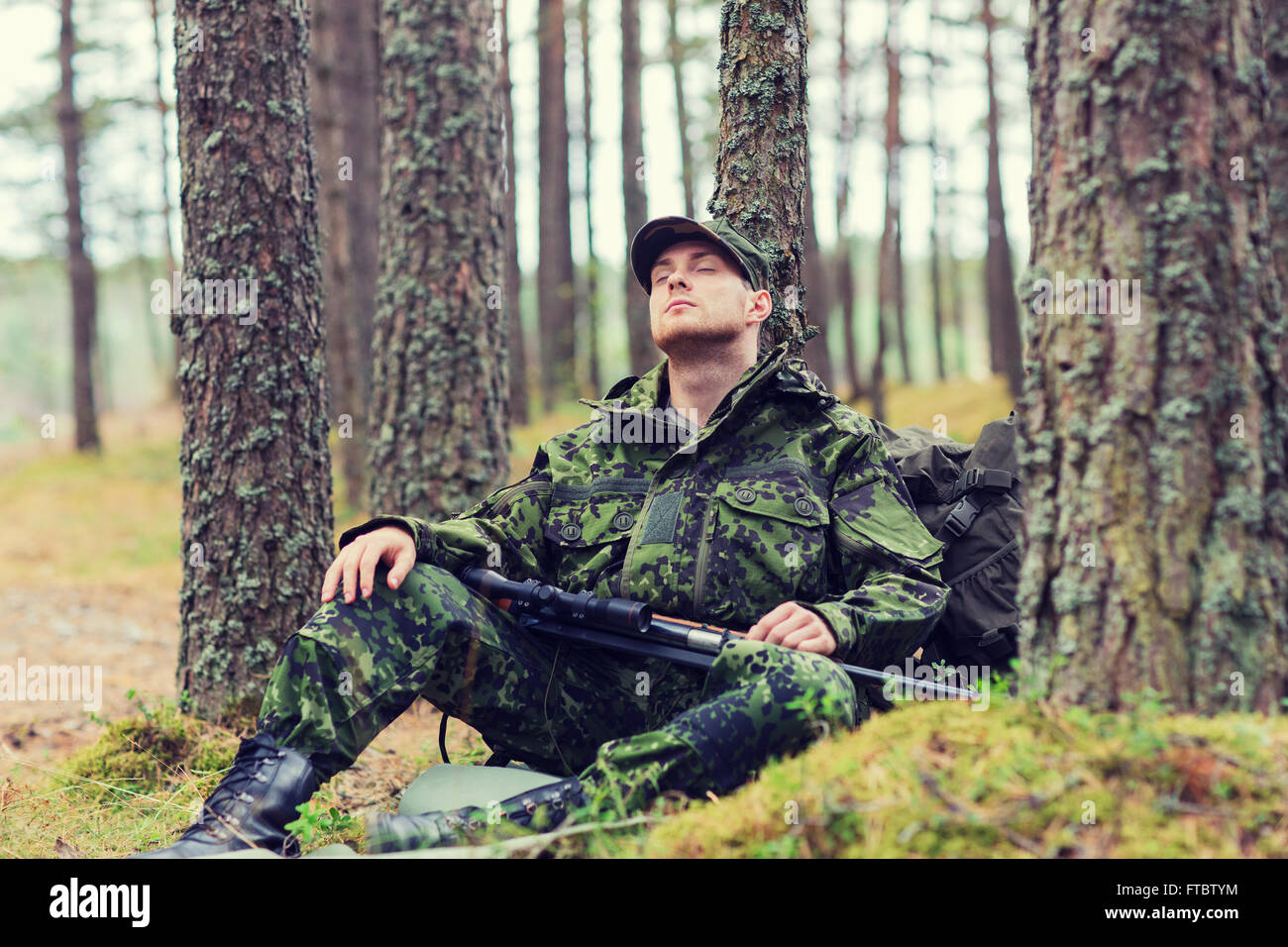 soldier or hunter with gun sleeping in forest Stock Photo - Alamy