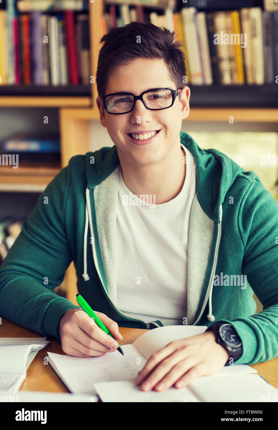 happy student writing to notebook in library Stock Photo - Alamy
