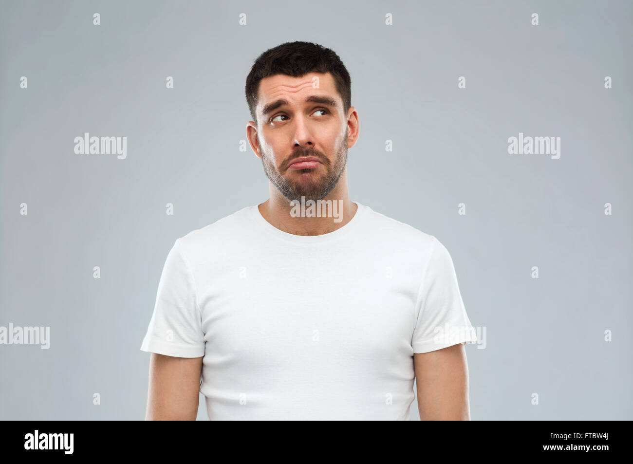 unhappy young man over gray background Stock Photo - Alamy