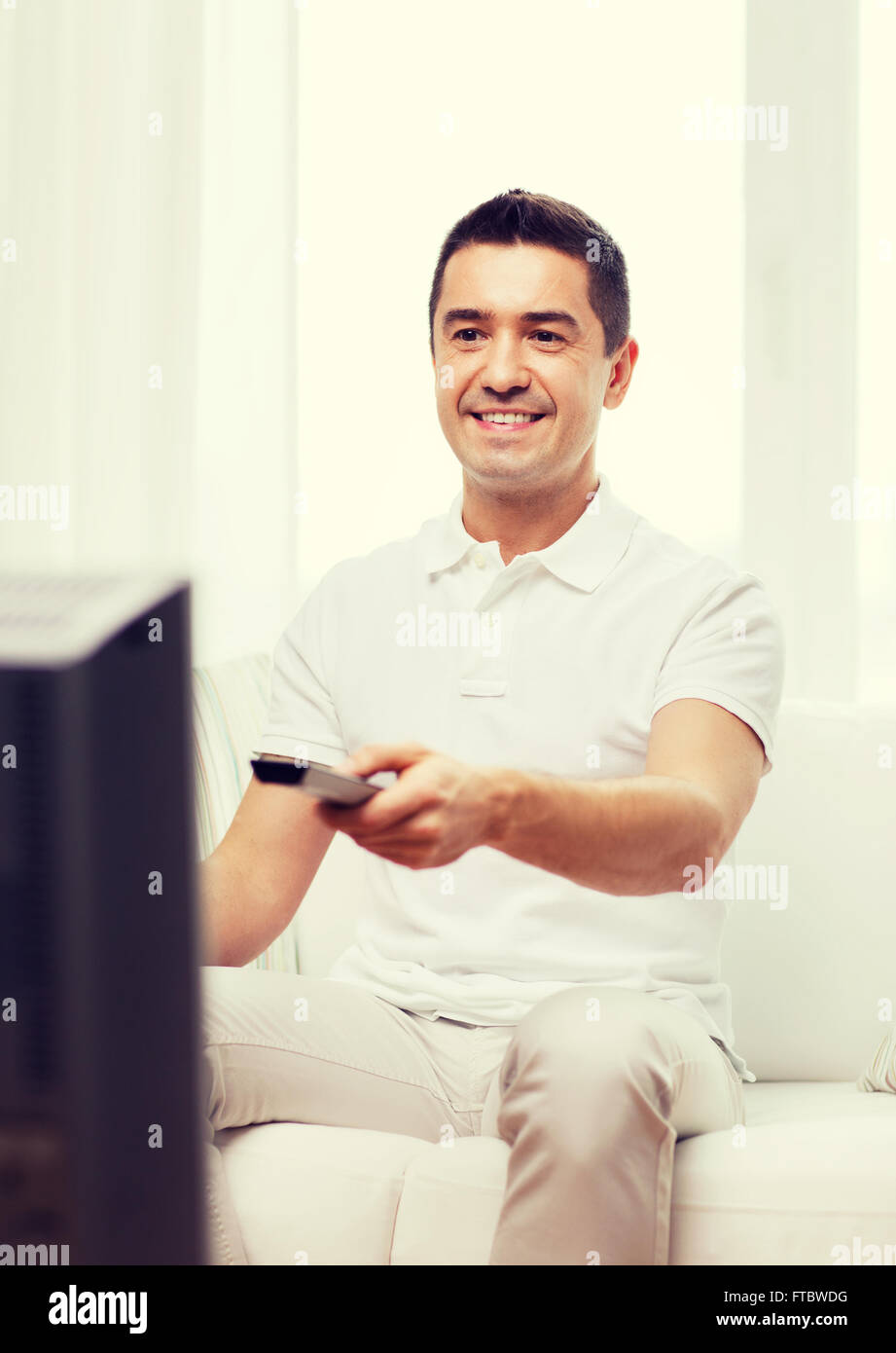 smiling man with remote control watching tv Stock Photo - Alamy