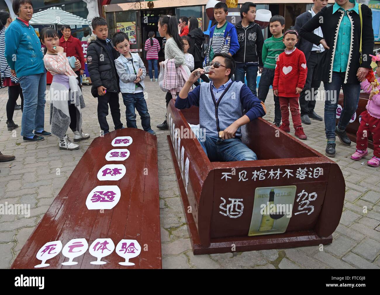 Chongqing, China. 27th Mar, 2016. A man sits in a mock coffin drinking ...