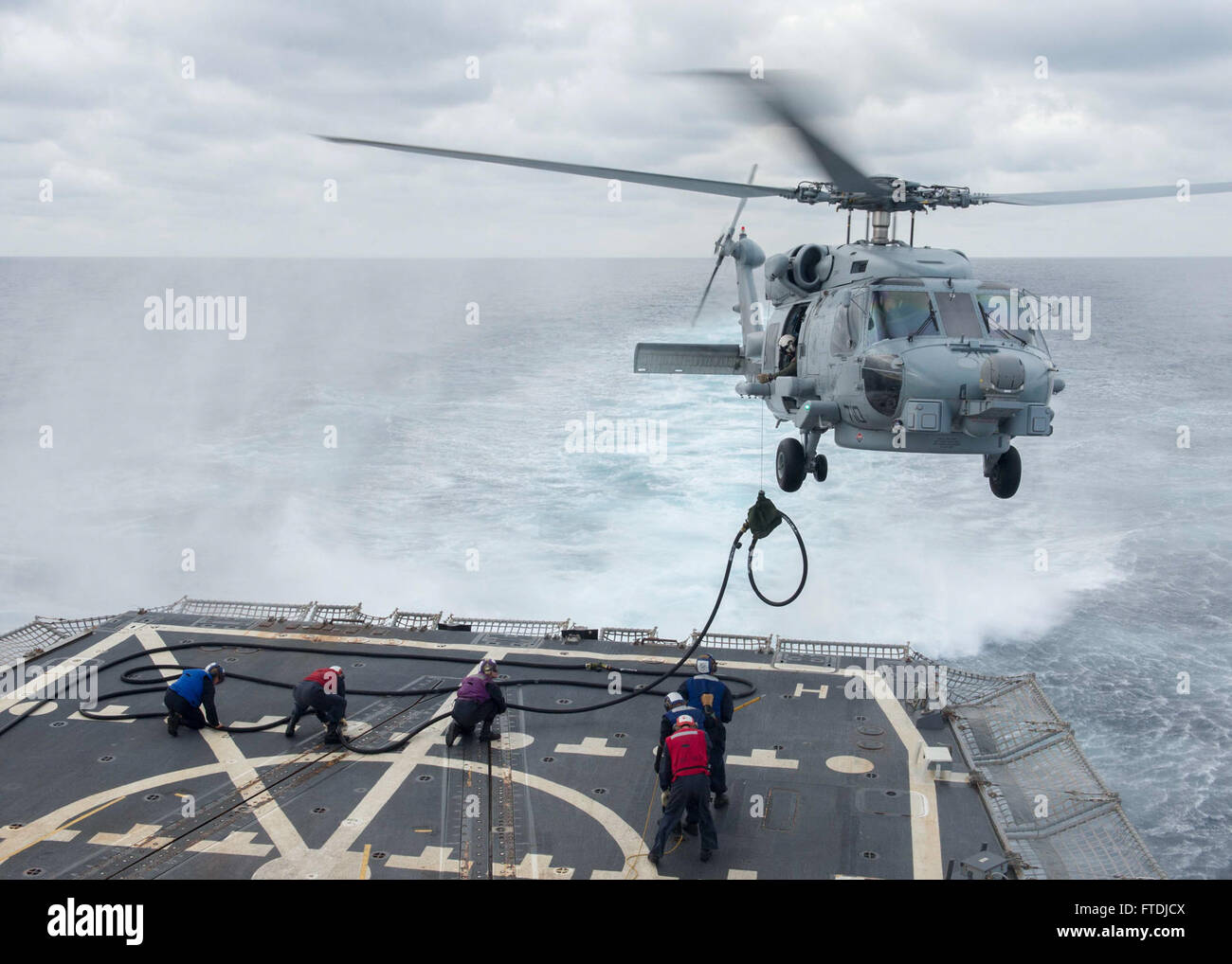 Sailors conduct a helicopter in-flight refueling from the USS Bulkeley ...