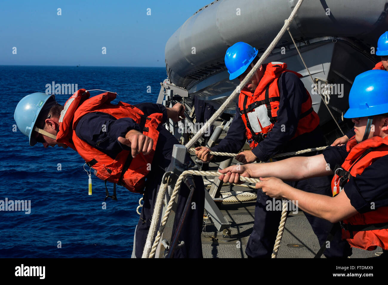 Sailors aboard the *USS Carney* (DDG 64) lower the pilot's ladder ...