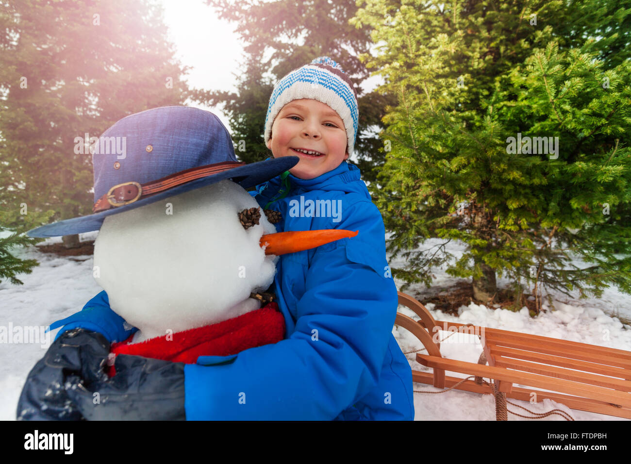 Little boy hug snowman in the park and smile Stock Photo - Alamy
