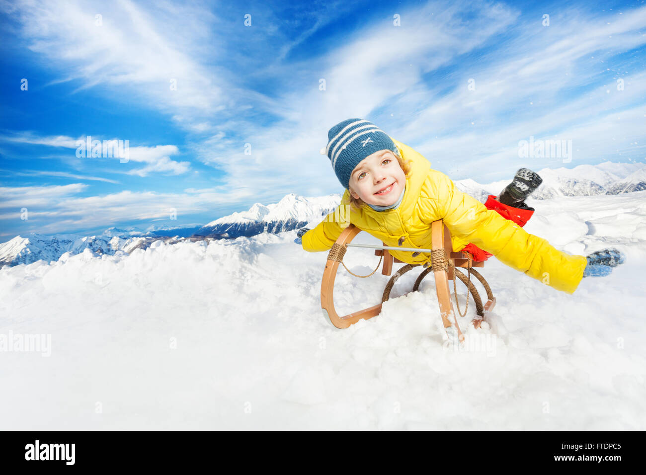Little boy lay on sledge smile and slide down Stock Photo - Alamy