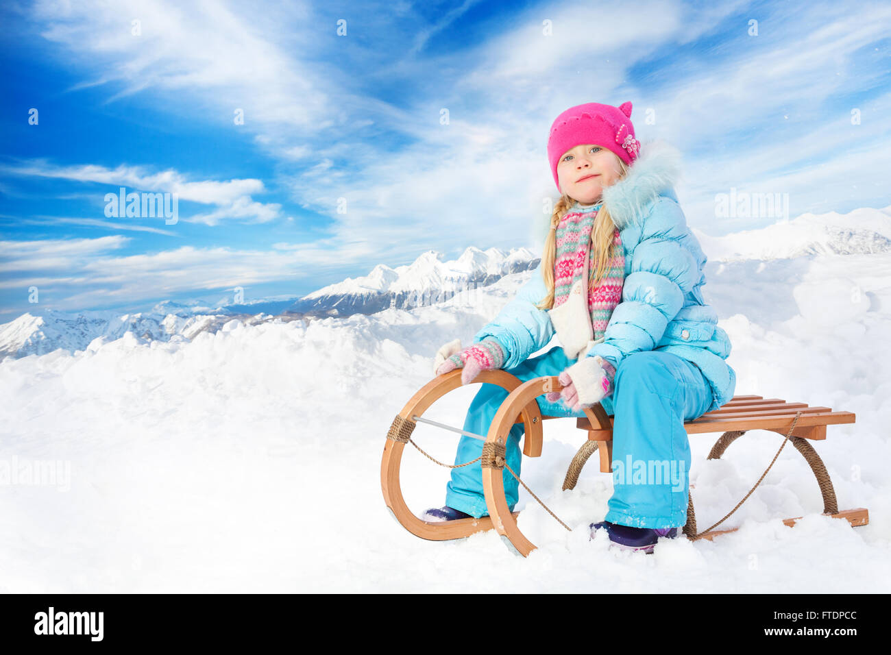 Happy little girl in blue on sledge Stock Photo - Alamy