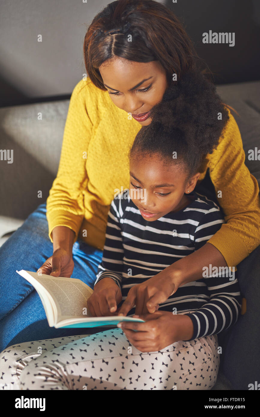 Overhead view mom and daughter reading book sitting in sofa at home ...