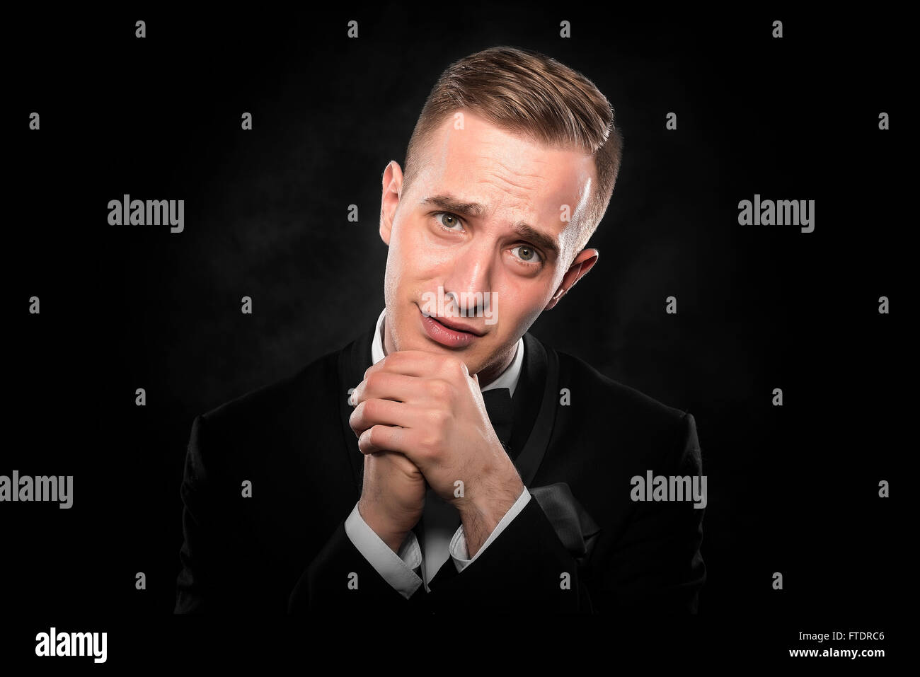 Young man asks for forgiveness on a dark background Stock Photo - Alamy