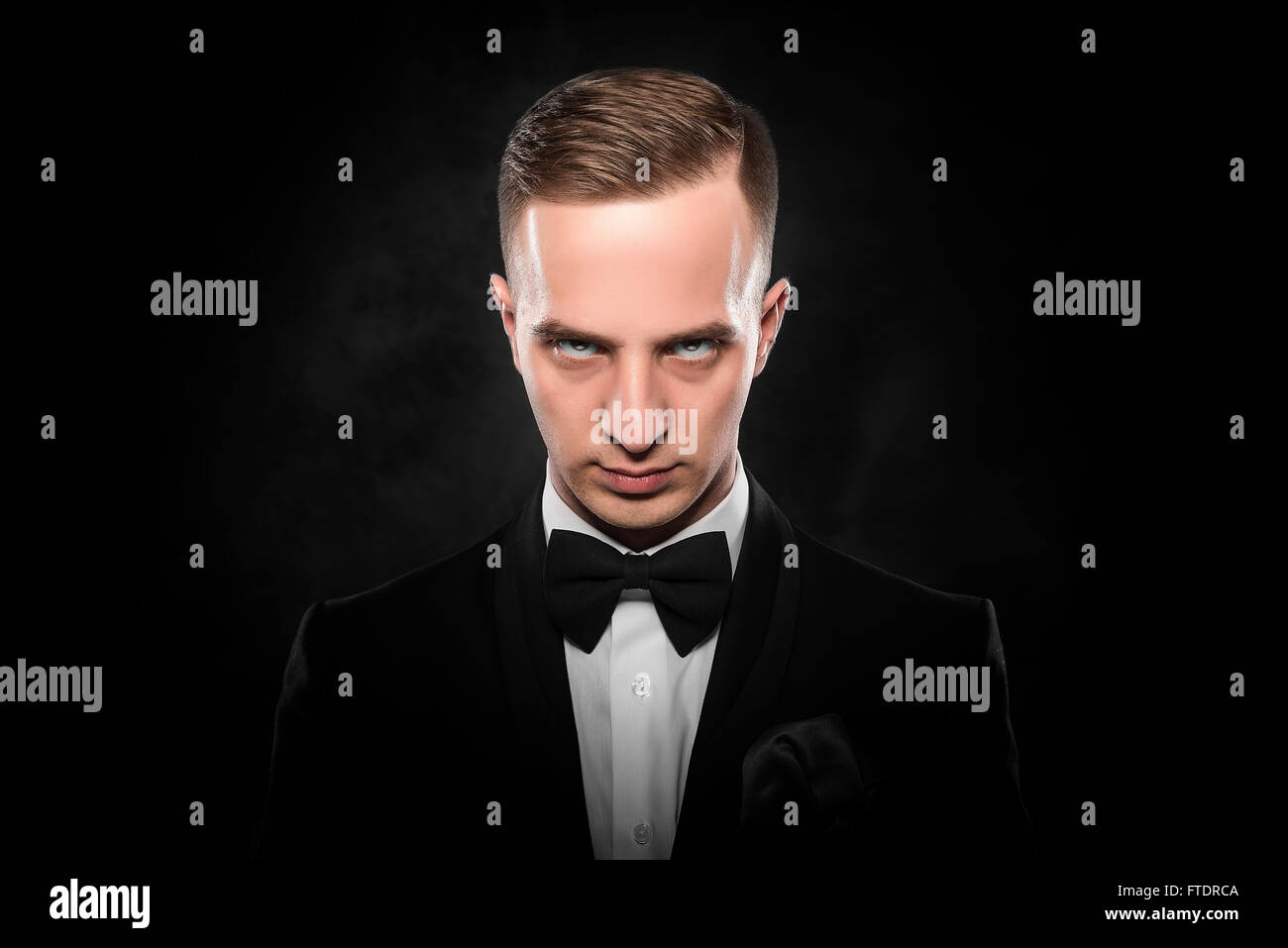 Elegant young man in suit looking frowning on dark background Stock ...