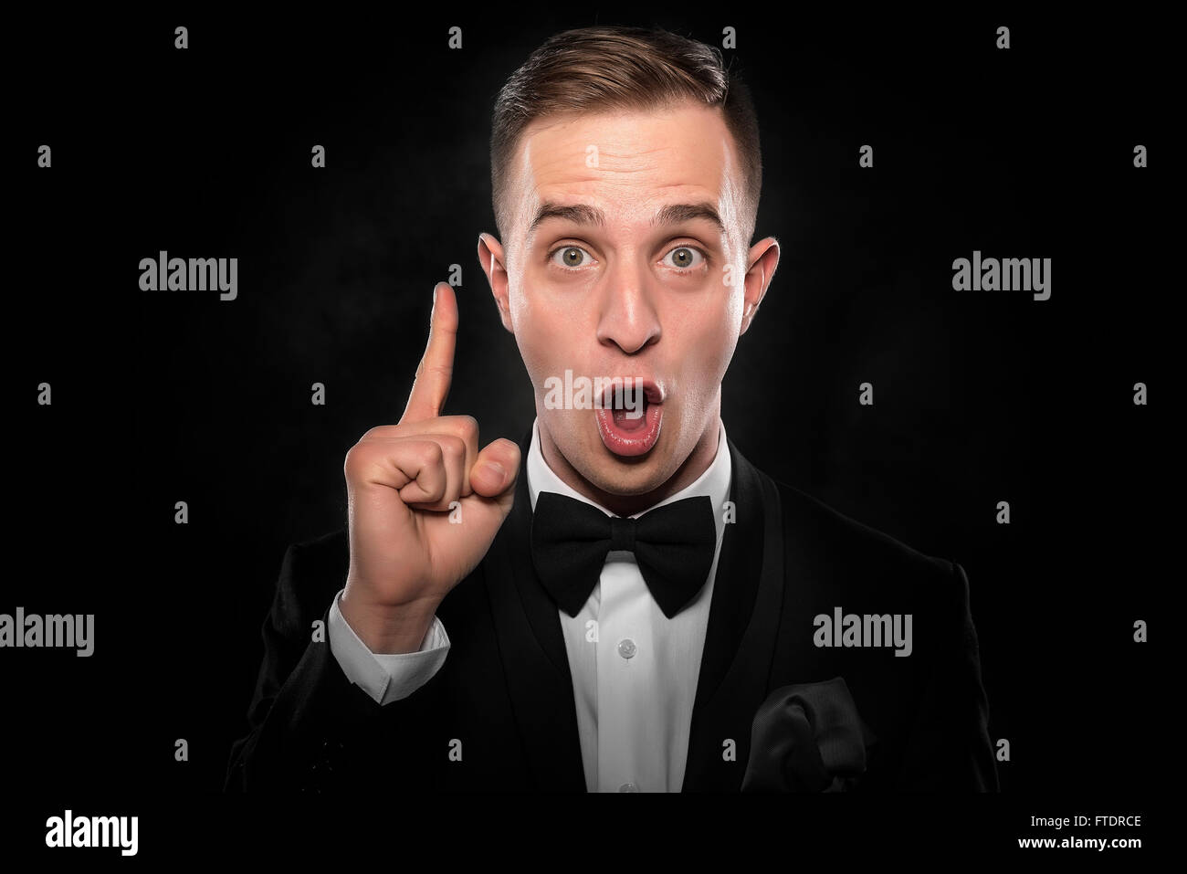 Idea. Young man shows finger up over darck background Stock Photo - Alamy