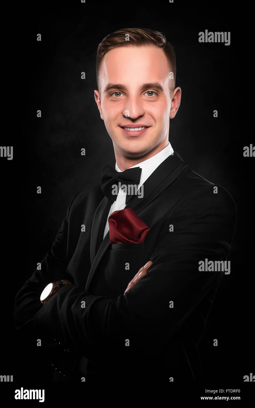 Young handsome man in black suit on dark background Stock Photo - Alamy