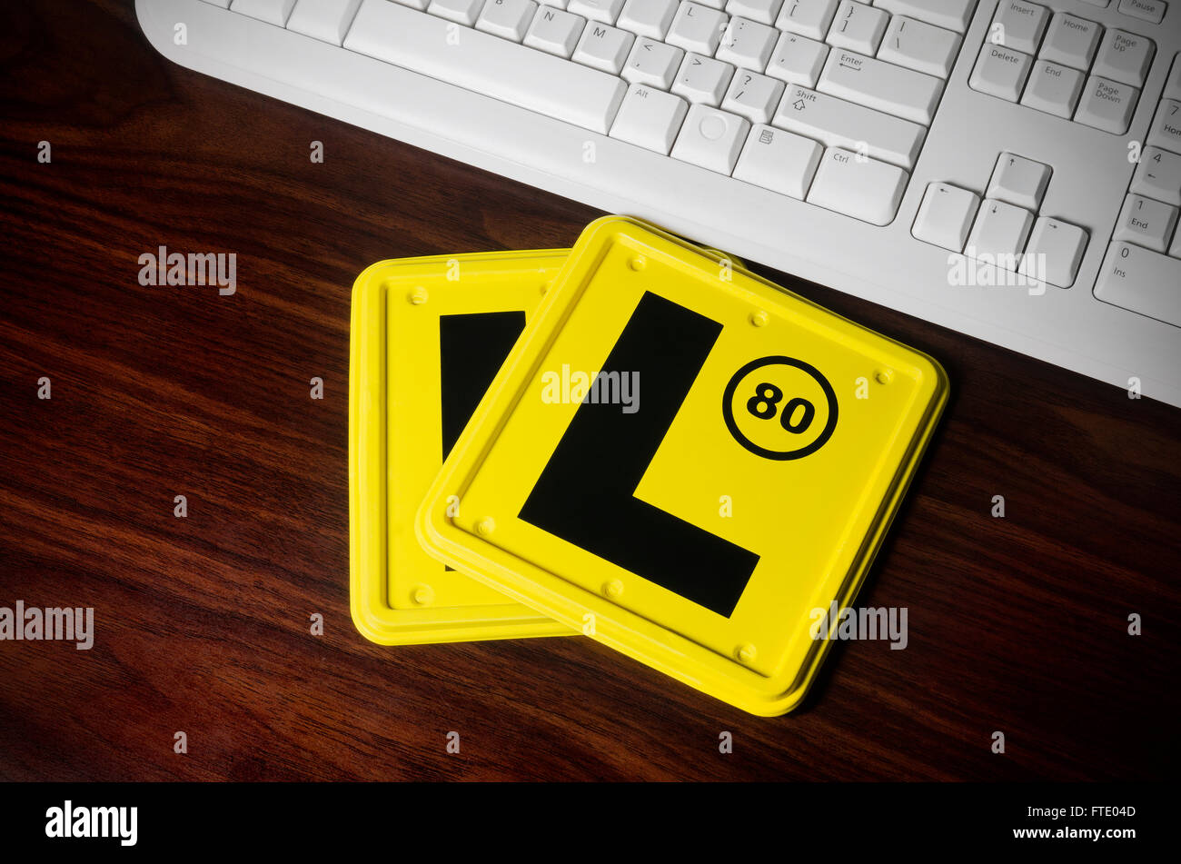 Two L plates laying on the computer desk next to the white keyboard ...
