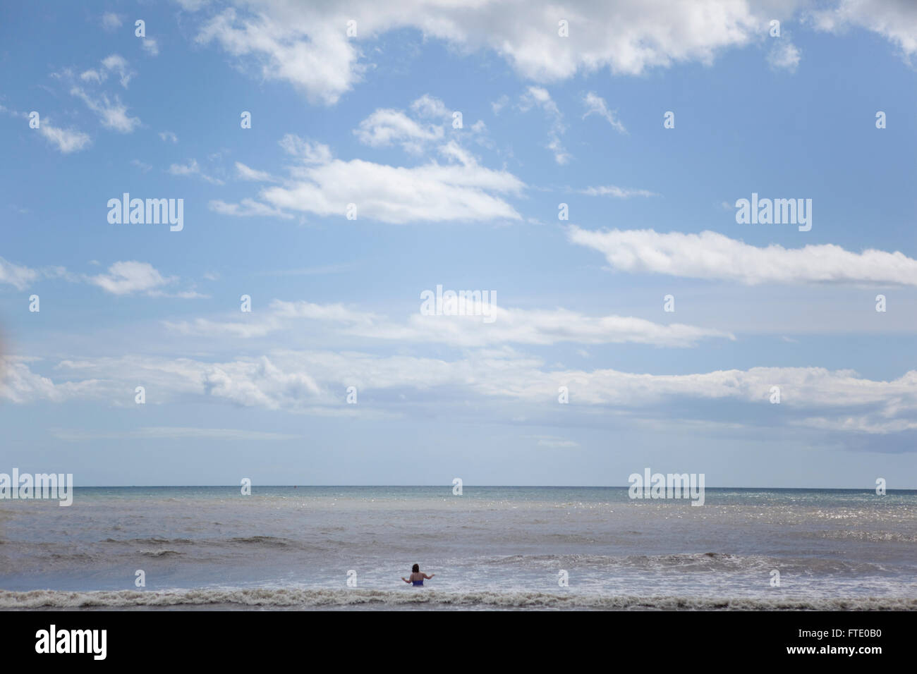A woman wades in to the sea alone preparing for a swim in the open ...