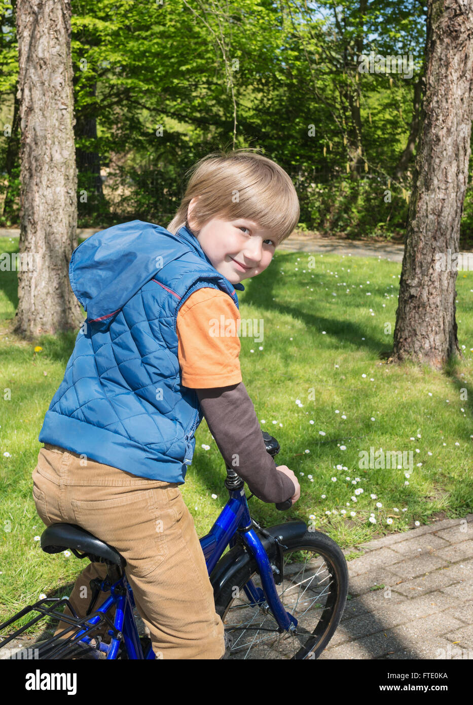 Smiling boy on a bicycle in a park Stock Photo - Alamy
