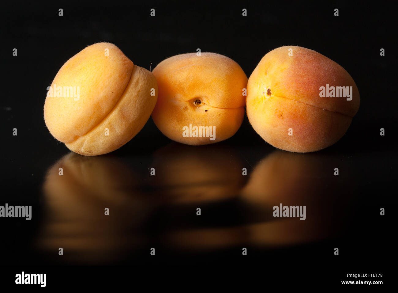 Apricots on black reflective background Stock Photo - Alamy