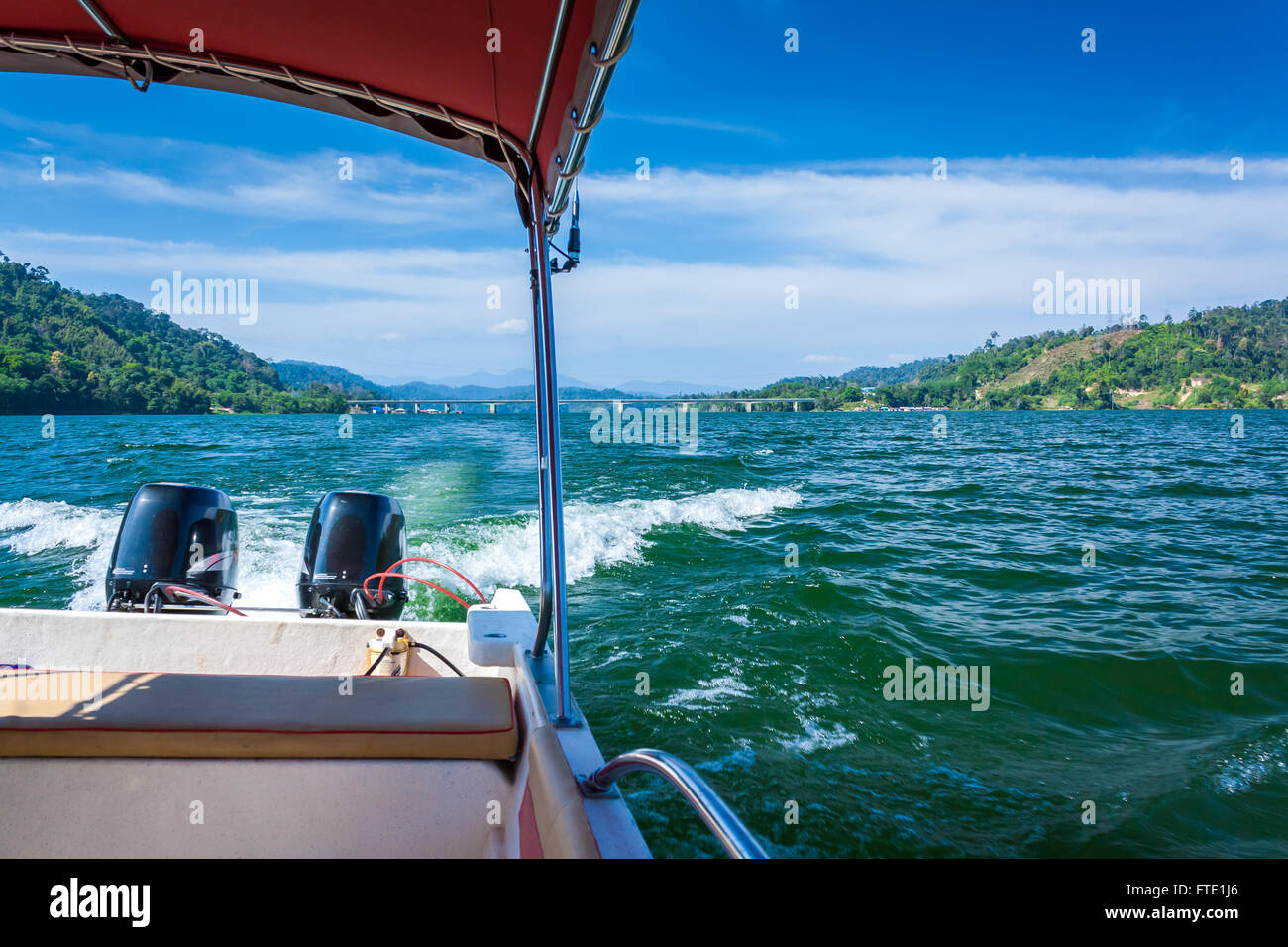 Back view of speed boat cruising on calm water, overlooking islands and ...