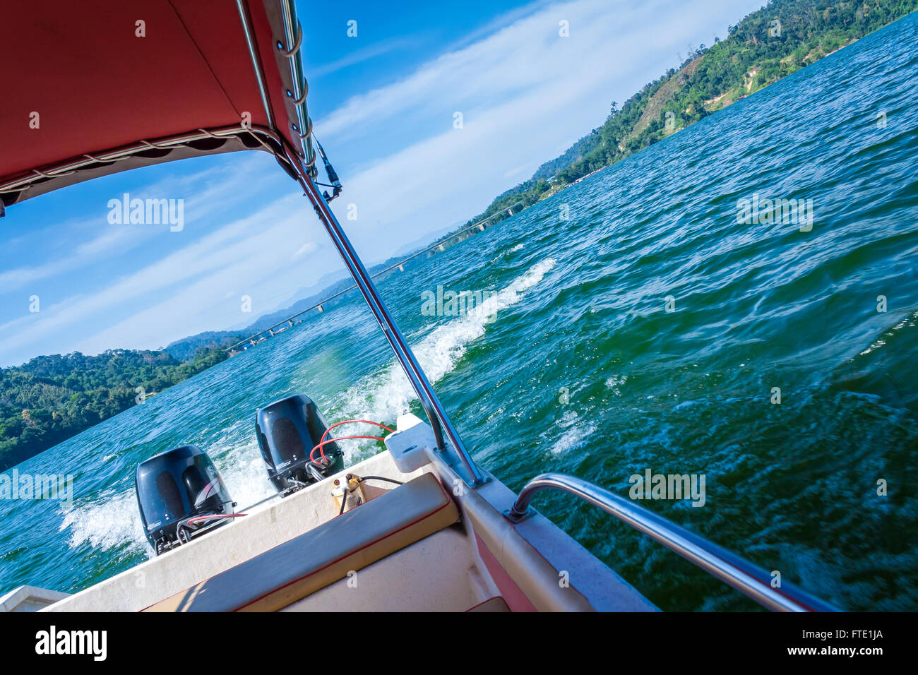 Back view of speed boat cruising on calm water, overlooking islands and ...