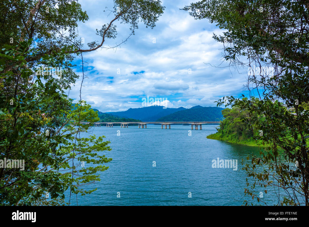 Tropical lake, forest and bridge in cloudy blue sky. Belum resort ...