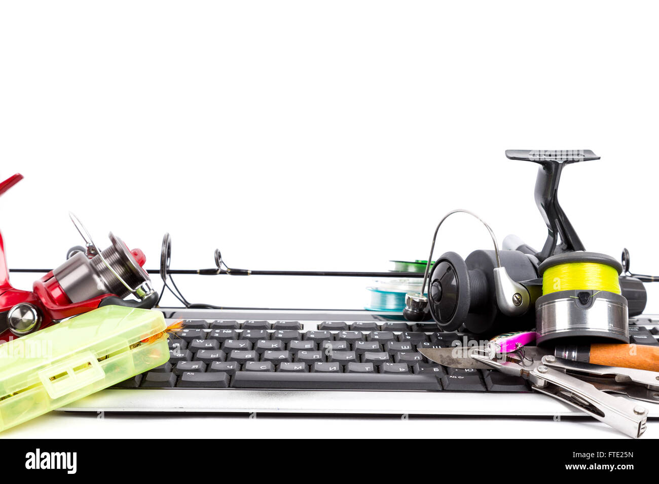 different fishing tackles on computer keyboard with white background ...