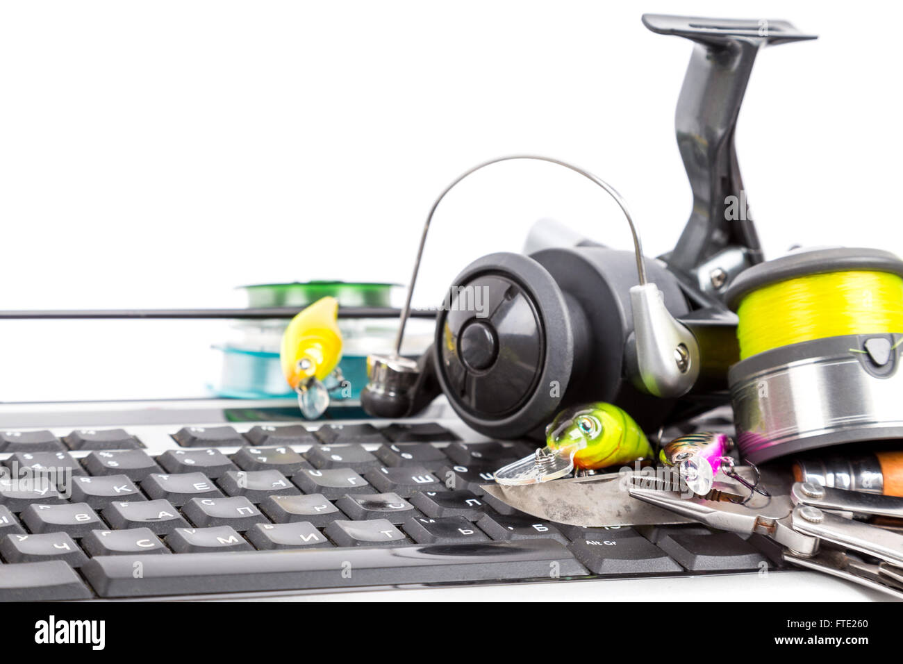 different fishing tackles on computer keyboard with white background ...