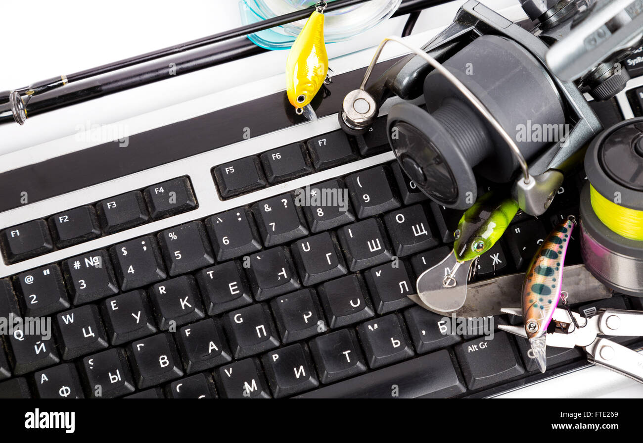 different fishing tackles on computer keyboard with white background ...