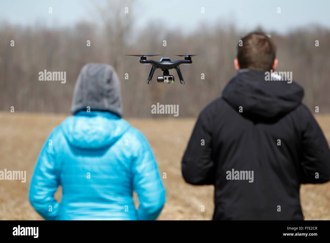 A couple watching a drone hover in front of them Stock Photo - Alamy