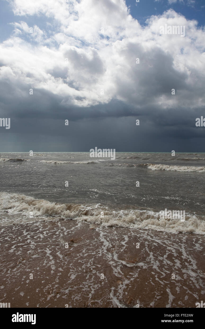 A heavy rain storm out at sea turns the sky deep dark grey as the rain ...