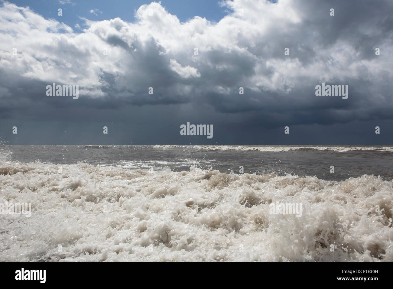 A heavy rain storm out at sea turns the sky deep dark grey as the rain ...