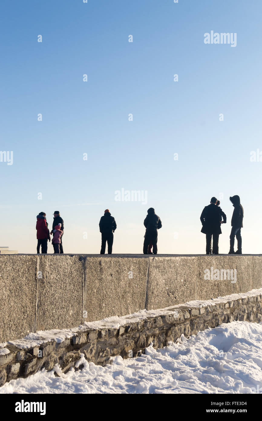 Groups of people stand on the edge of the horizon in a colour abstract ...