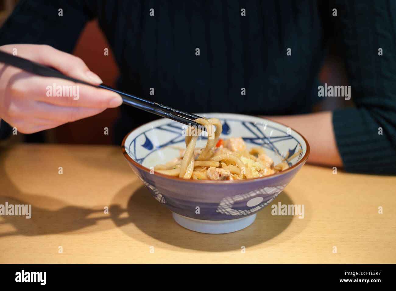 Woman eating traditional japanese udon noodles with sticks. Horizontal ...