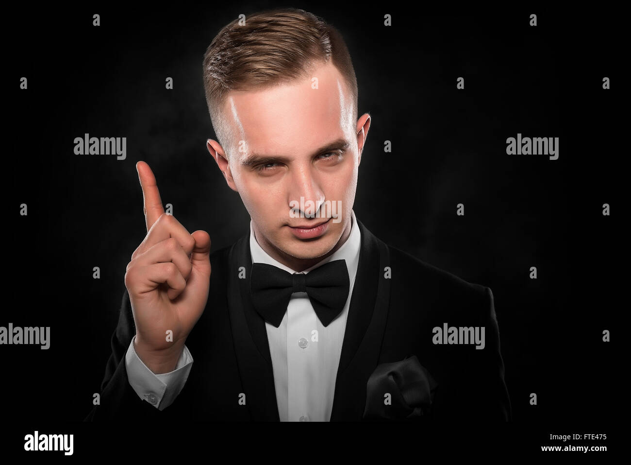 Idea. Young man shows finger up over darck background Stock Photo - Alamy
