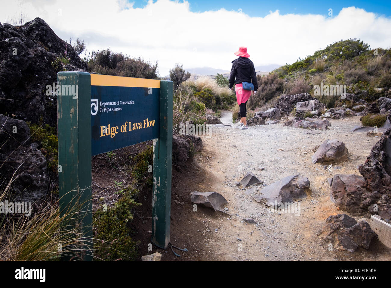 A woman walking past a sign showing the edge of lava flows from Mt ...