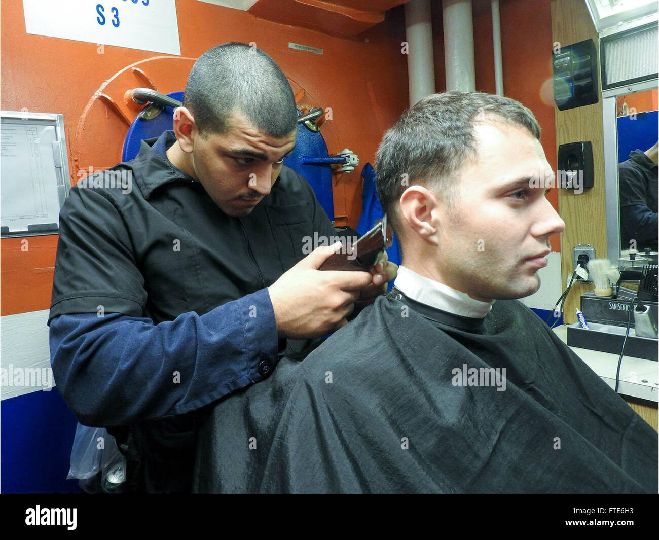 A photo of Ship's Serviceman 2nd Class Isaac Payne cutting the hair of ...