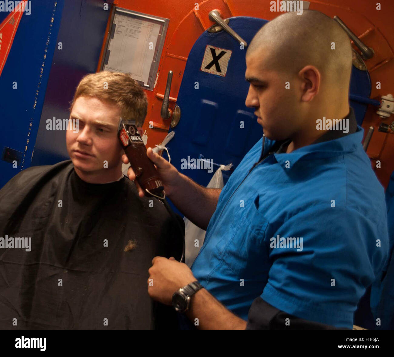 Ship's Serviceman 2nd Class Isaac Payne provides a haircut to Lt. j.g ...