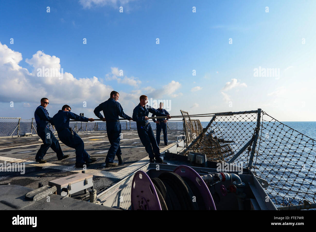 Sailors aboard the USS Monterey (CG 61) are seen lifting a safety net ...