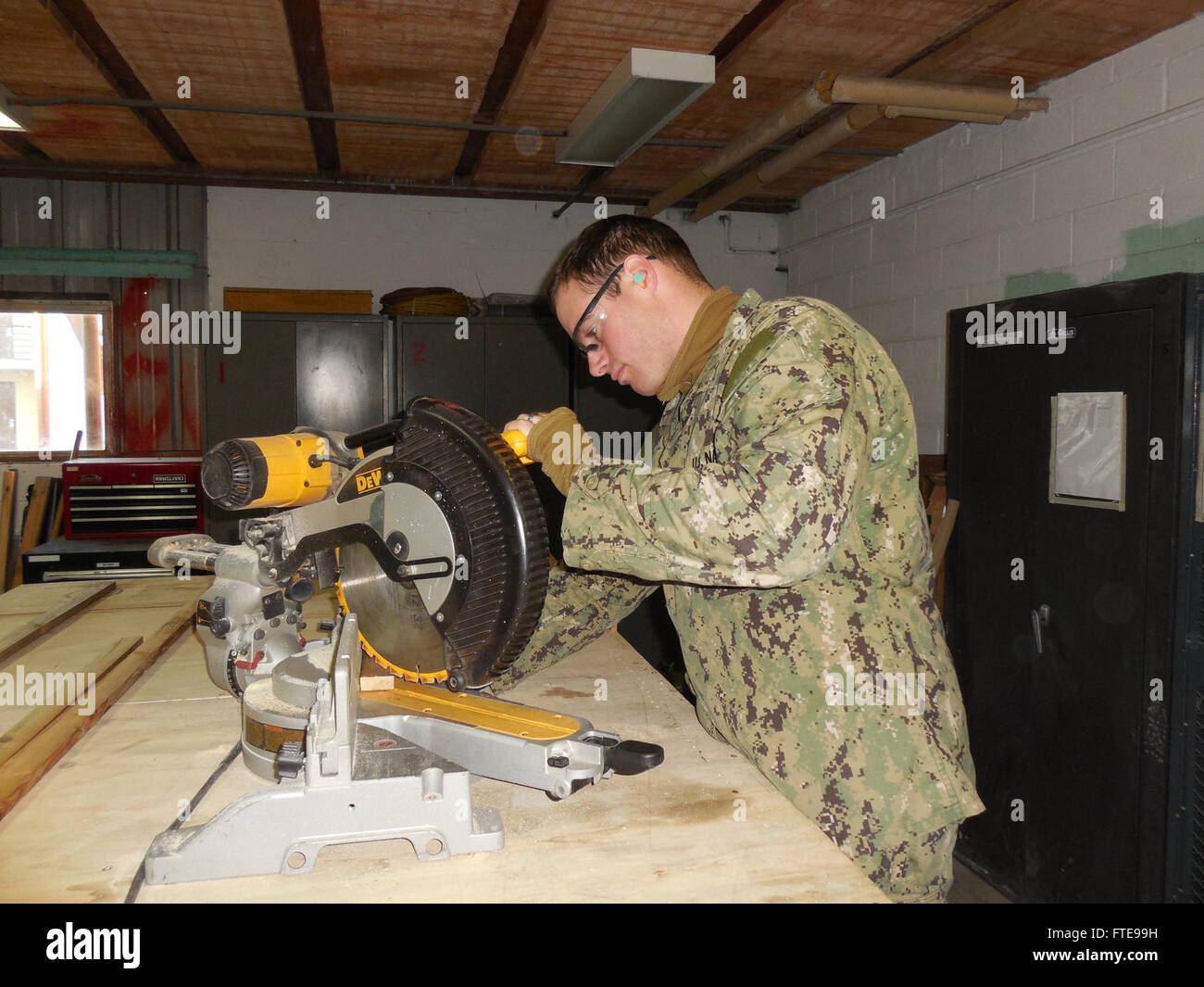 Steelworker Constructionman Ryan Long of the U.S. Navy operates a miter ...