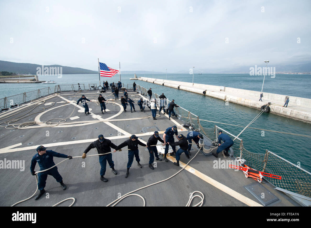 A photograph of sailors aboard the USS Stout (DDG 55) heaving mooring ...