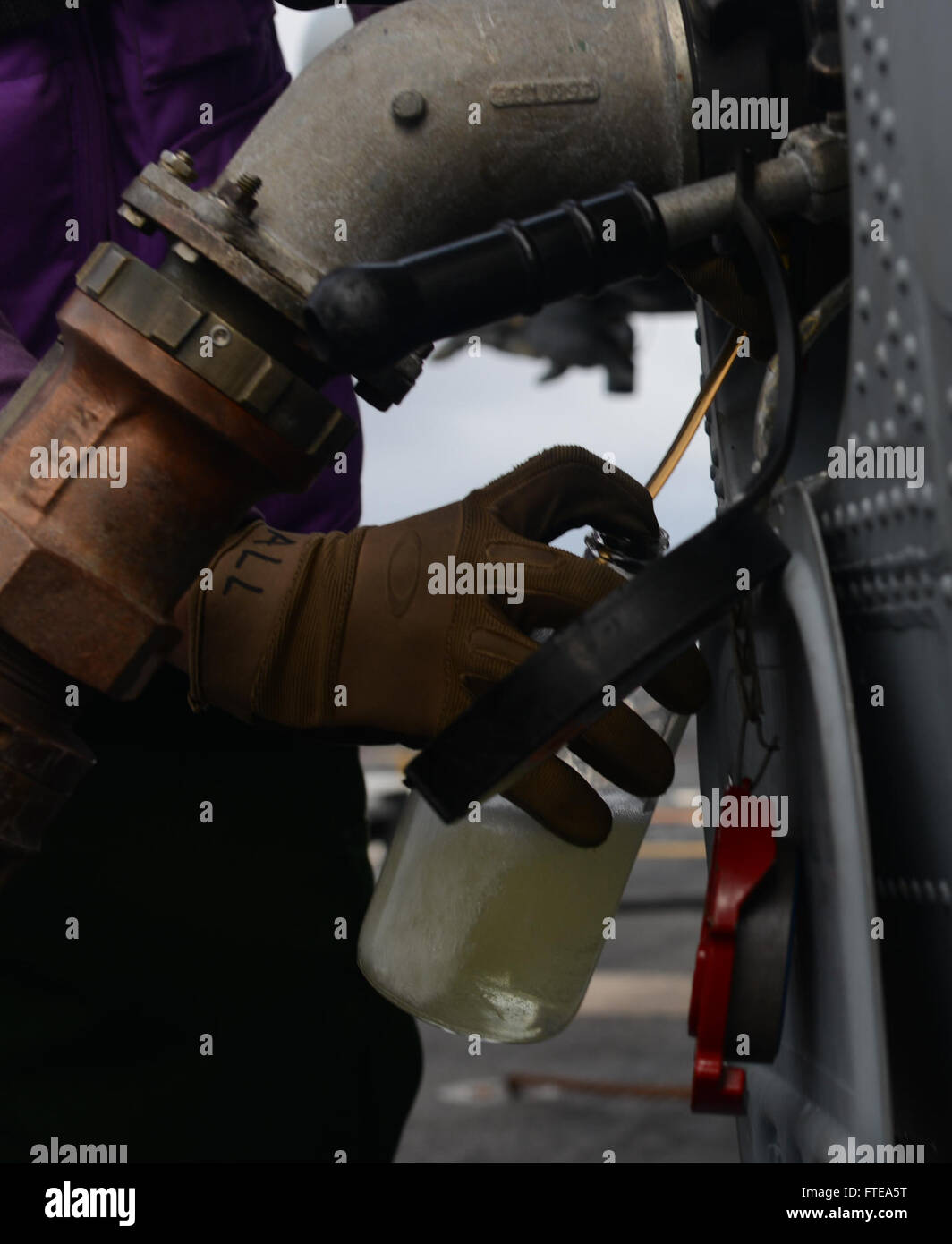 A U.S. Marine performs a fuel sample check on a UH-1 Huey helicopter ...