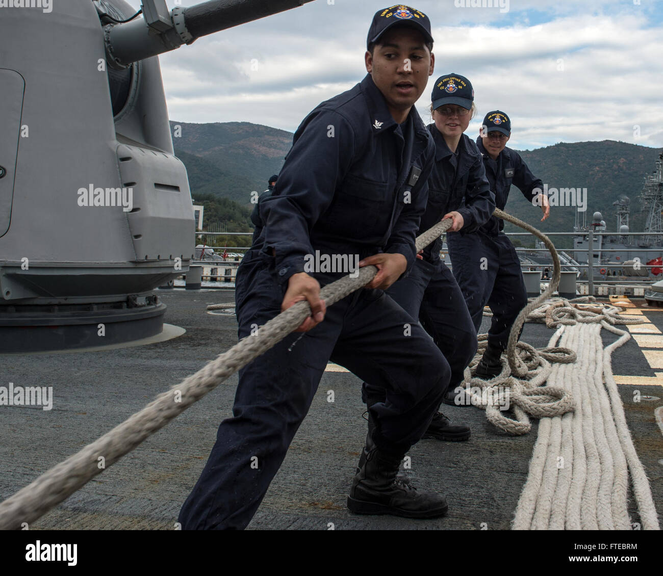 Sailors aboard the USS Philippine Sea (CG 58) heave a line as the ...