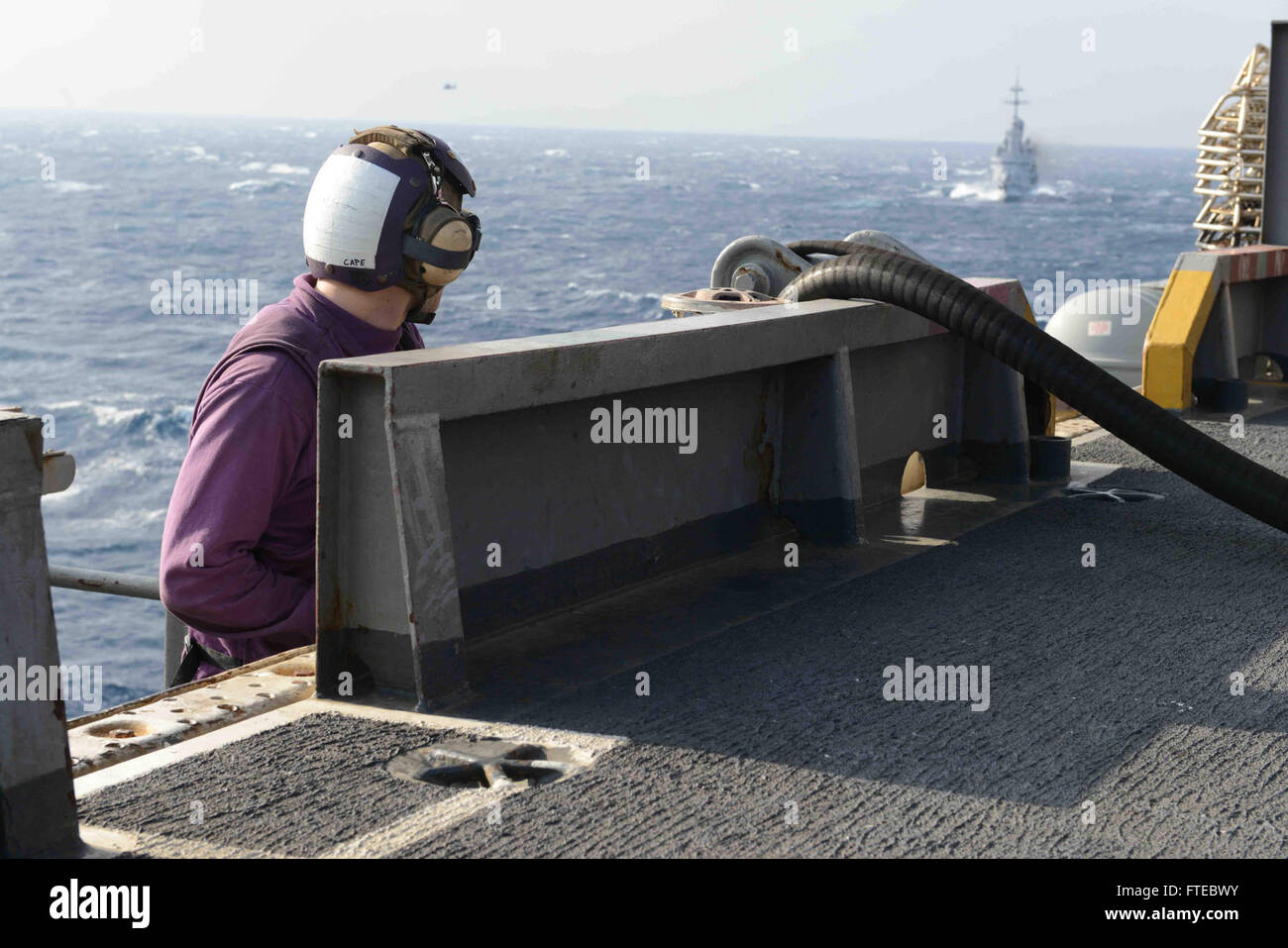 This photo captures a U.S. Navy sailor observing the French frigate FS ...