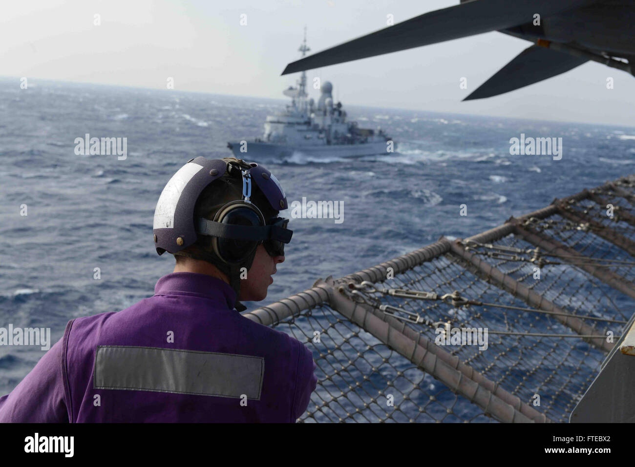 This image shows a U.S. Navy Sailor observing as the French frigate FS ...