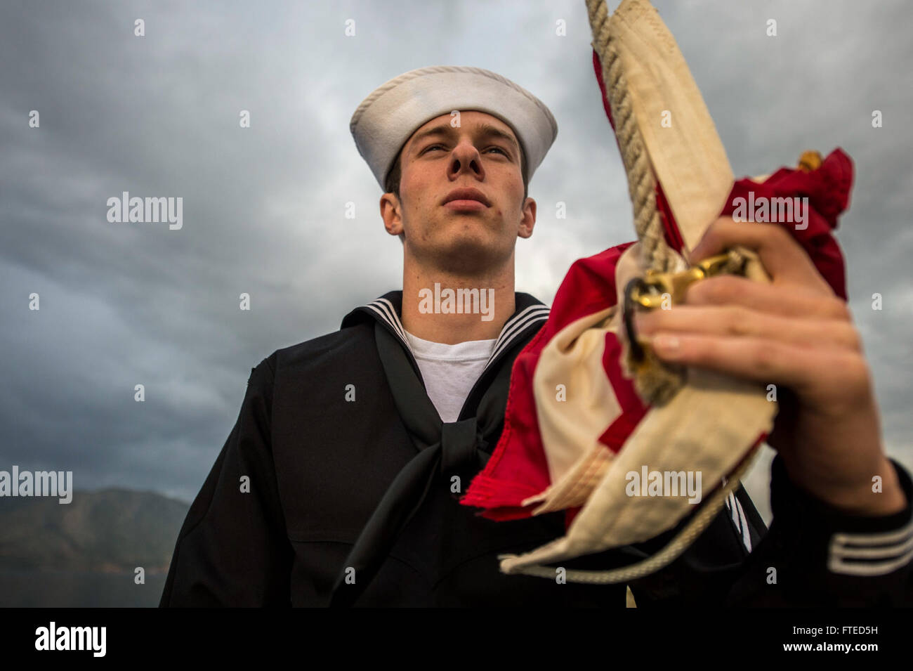 A U.S. Navy Logistics Specialist Seaman raises the Navy jack aboard the ...
