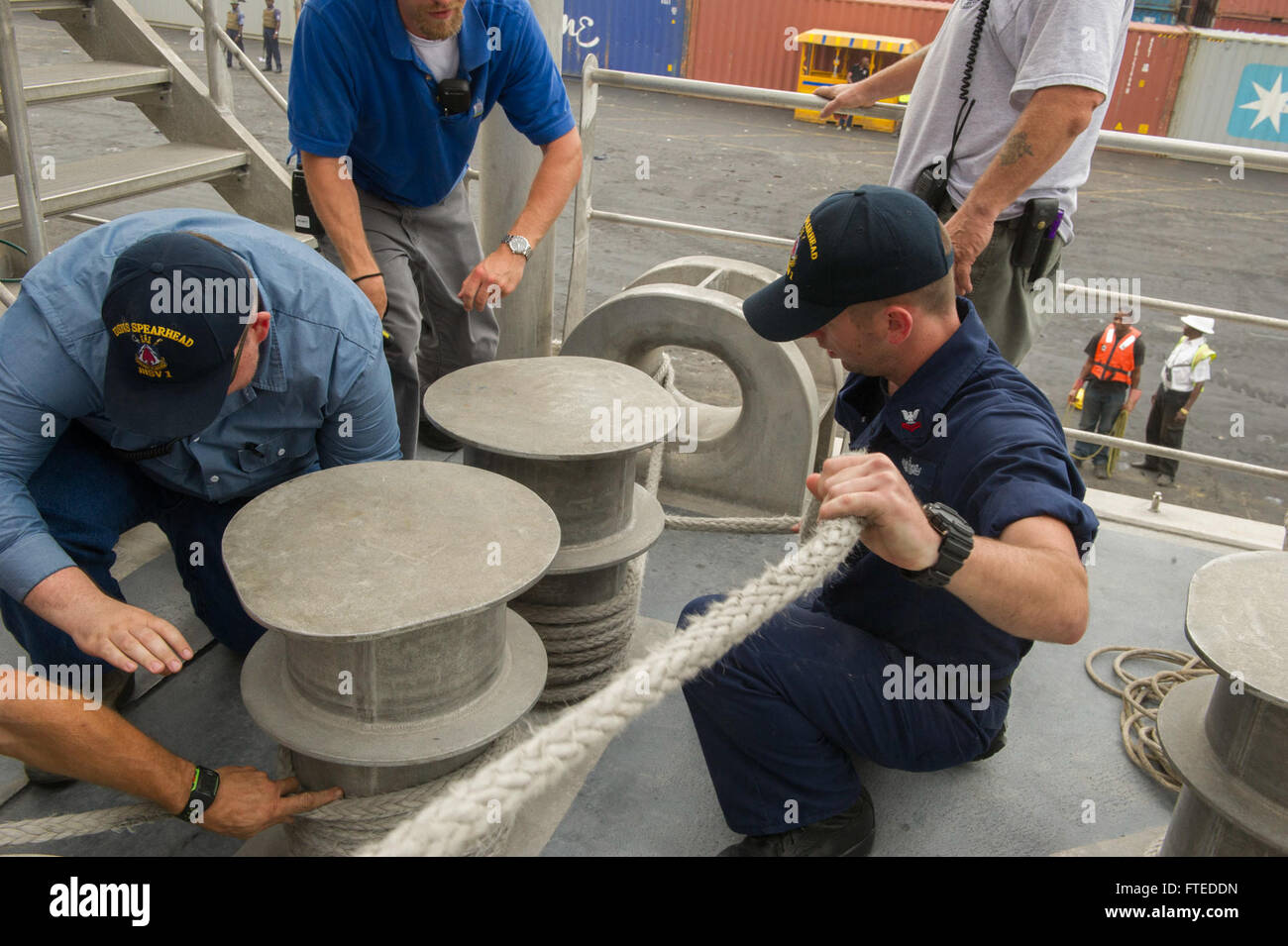 The image shows sailors and civil service mariners heaving mooring ...