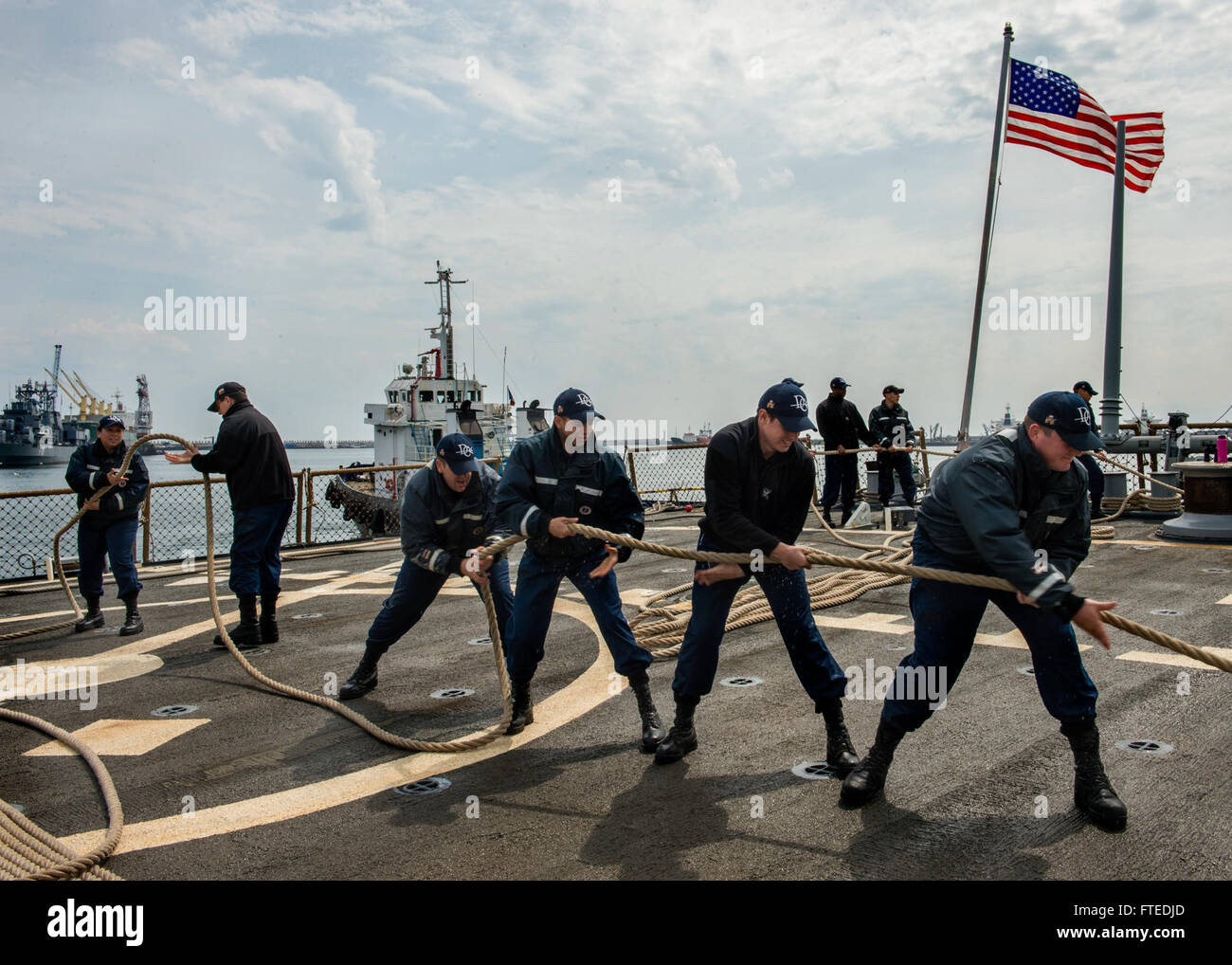 Sailors aboard the USS Donald Cook (DDG 75) haul in mooring lines as ...