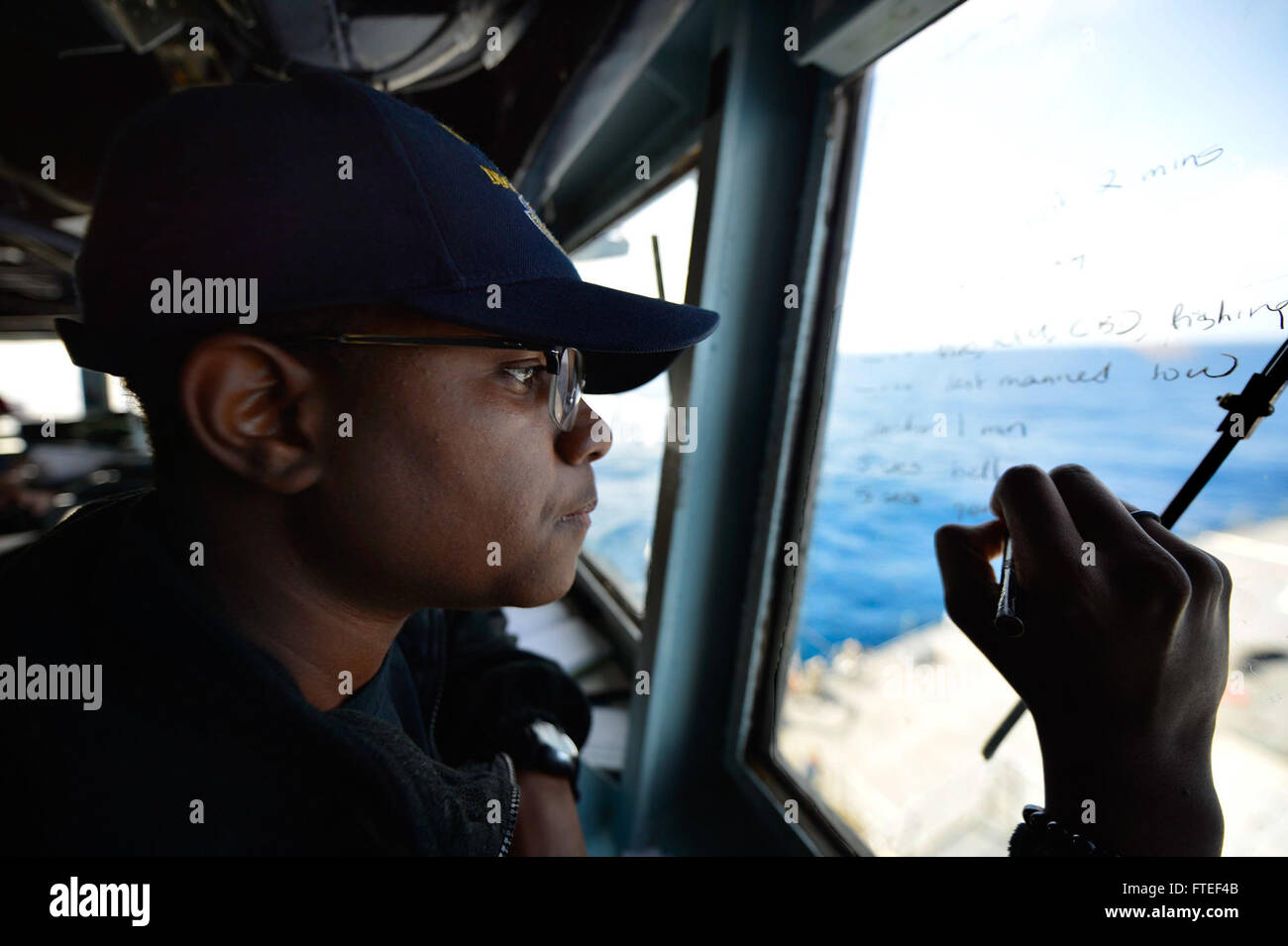 Ensign Javen Davis of the USS Nitze (DDG 94) writes navigation notes on ...