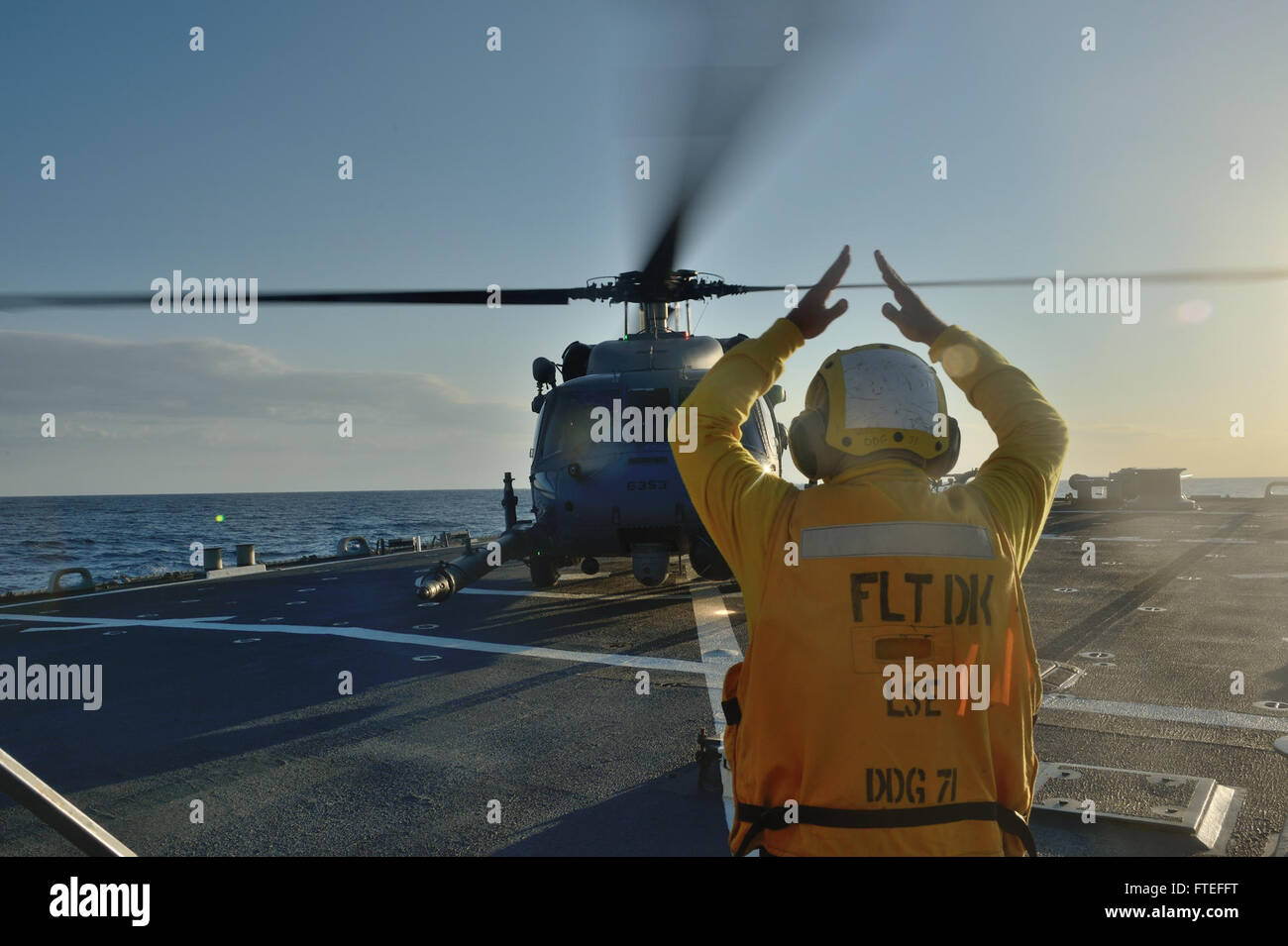 This image shows Boatswains Mate 2nd Class Billie Johnson signaling a U ...
