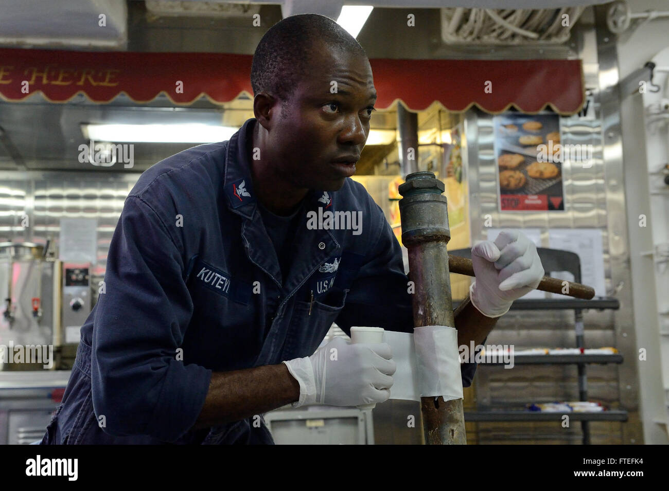 Damage Controlman 3rd Class Bamidele Kuteyi demonstrates how to apply a ...